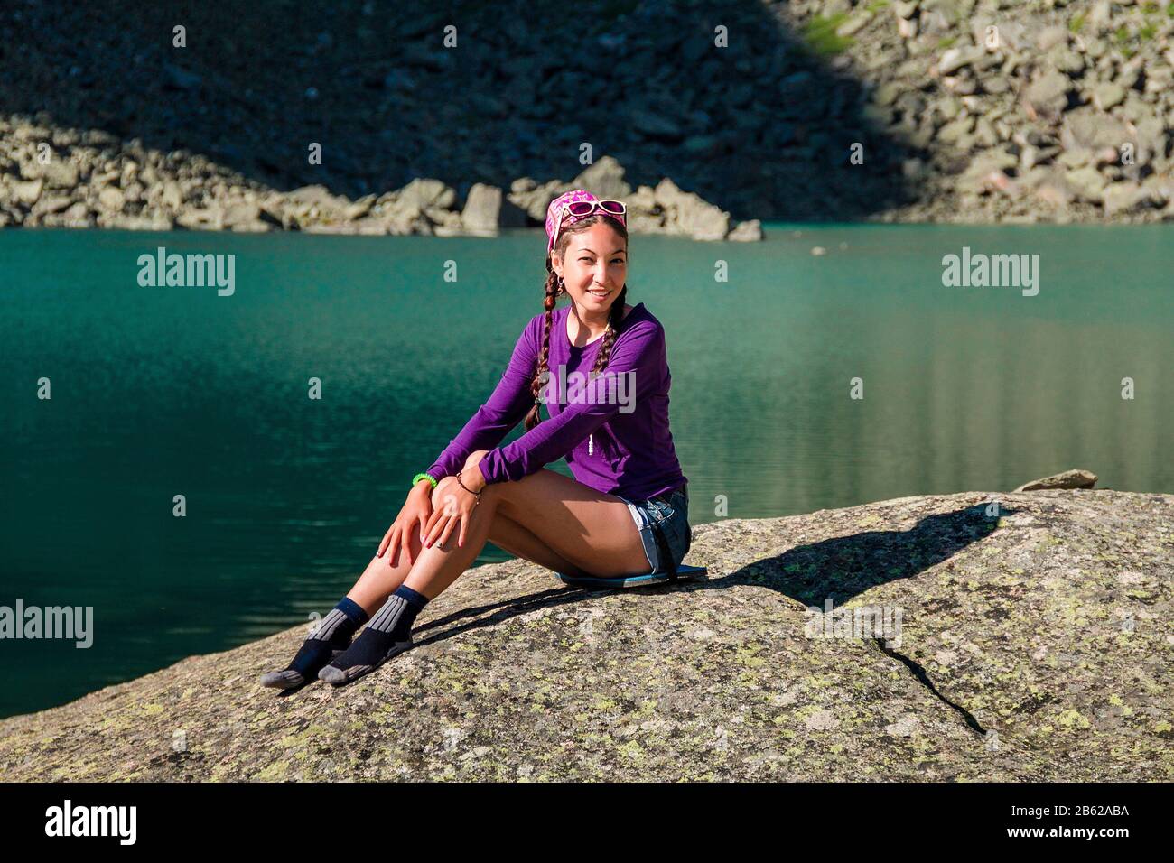 mountain Alpine lake and a girl sitting on the stone Stock Photo - Alamy