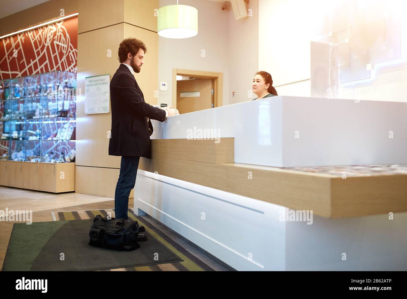 female receptionist giving information to guest upon arrival at hotel ...