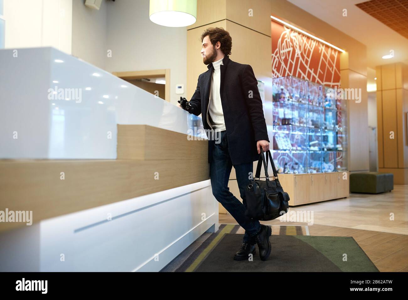 young handsome male tourist paying for the room, leaning on the ...