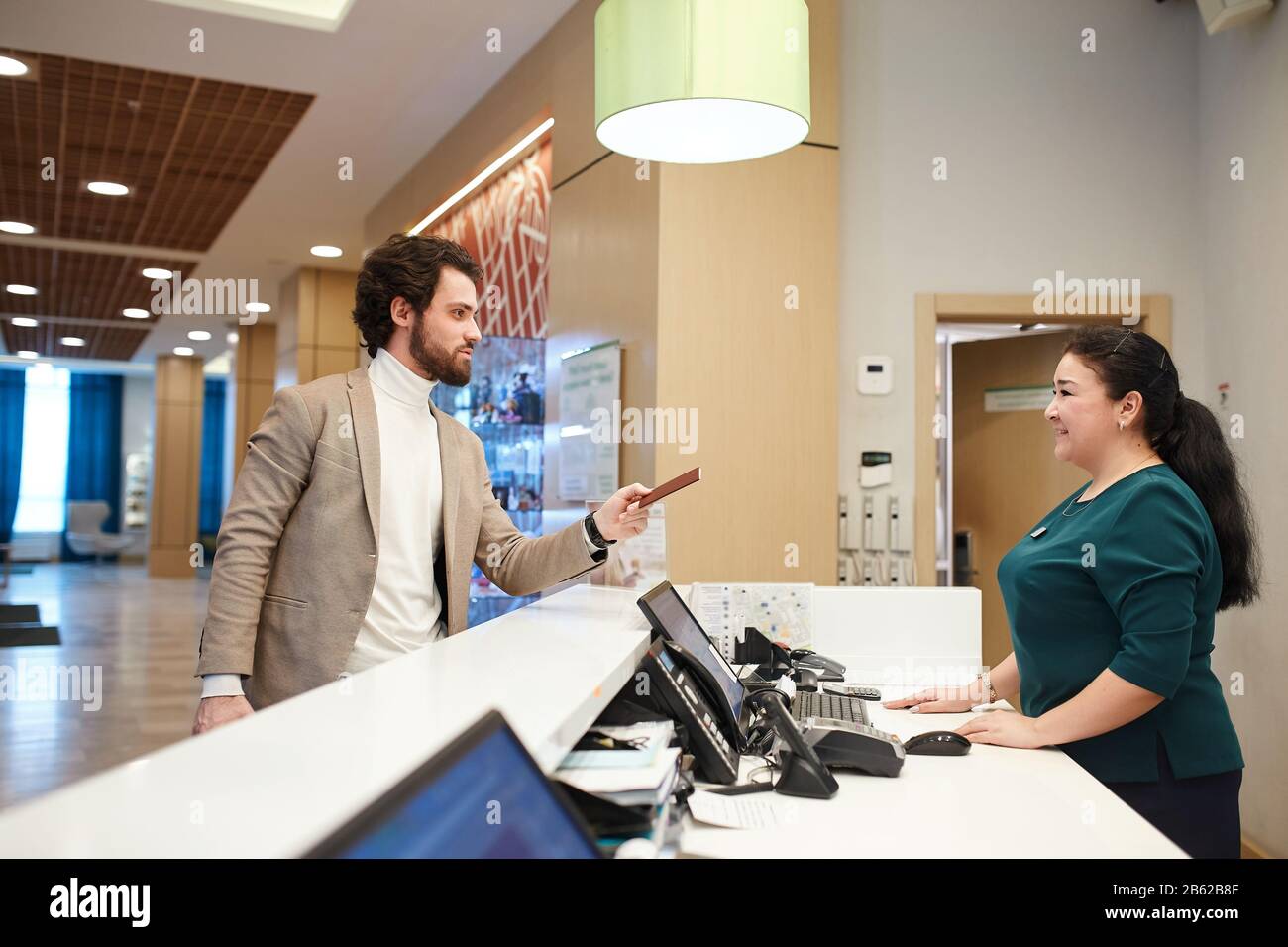 young friendly manager checking the guest in, registration concept ...