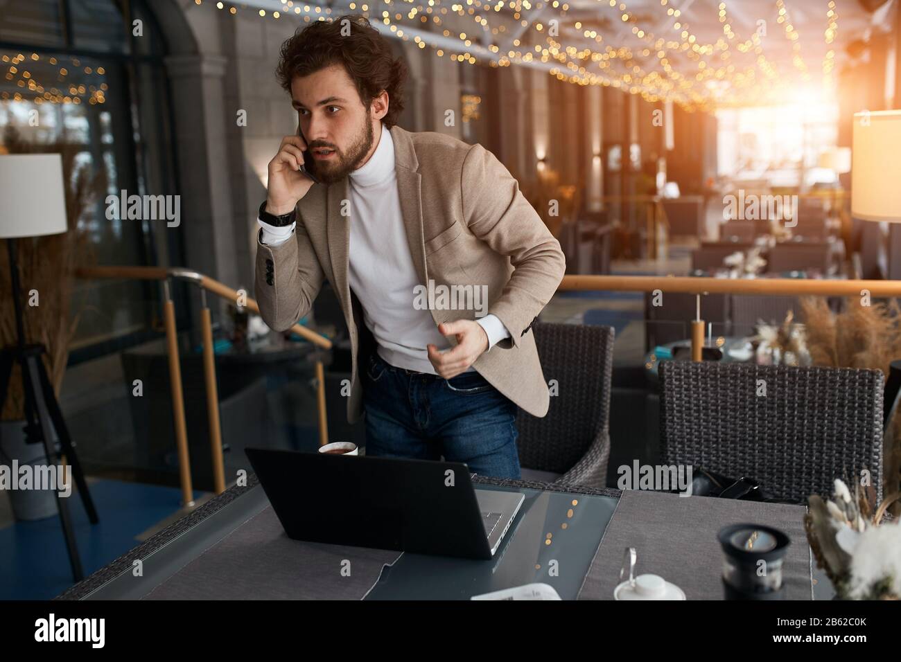 young elegant man standing behind the table and offering goods to ...