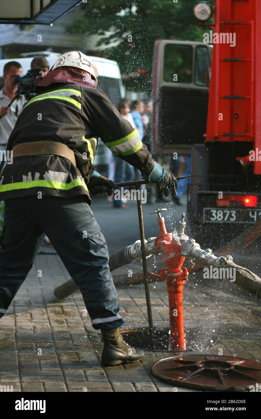 Firefighters connect hoses to a hydrant on the street near a burning ...