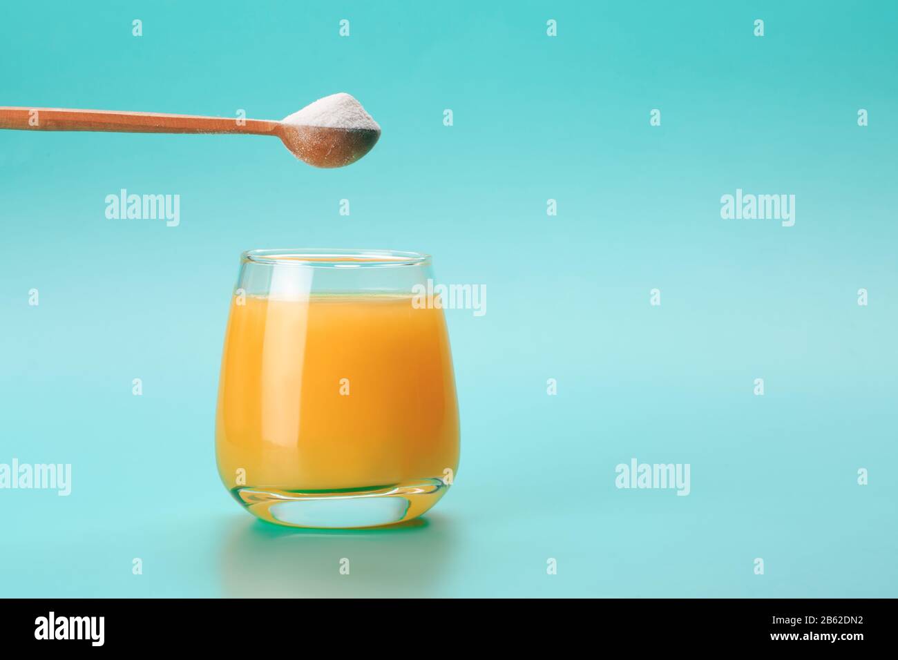 Orange juice with spoon of protein or collagen. Food supplement concept ...