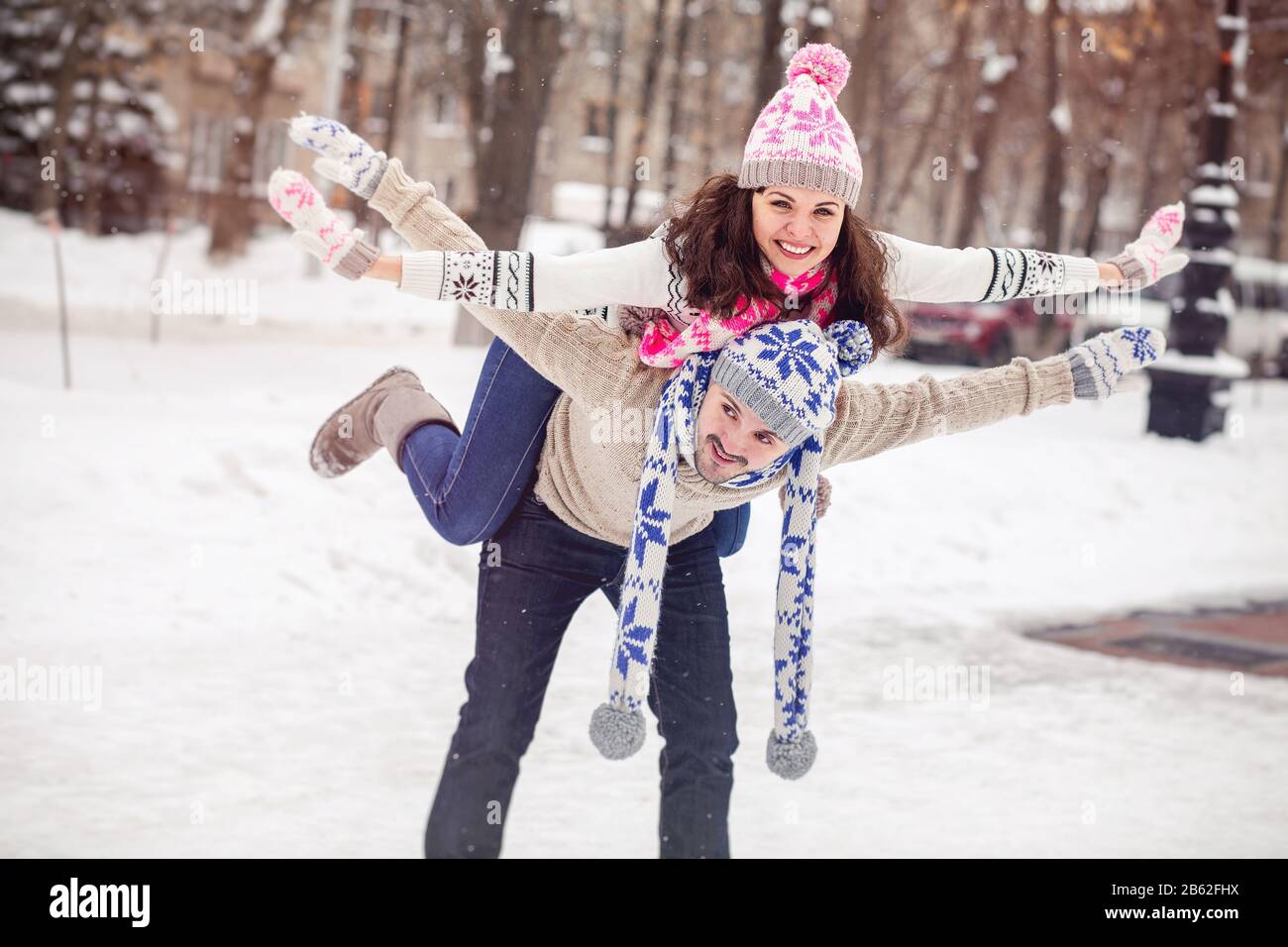 Happy young couple walking in winter park piggyback Stock Photo - Alamy