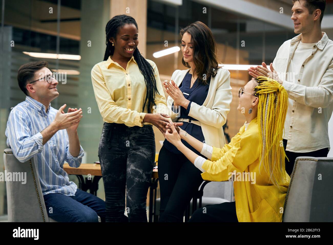 cheerful pleasant colleagues congratulating their friend with promotion ...