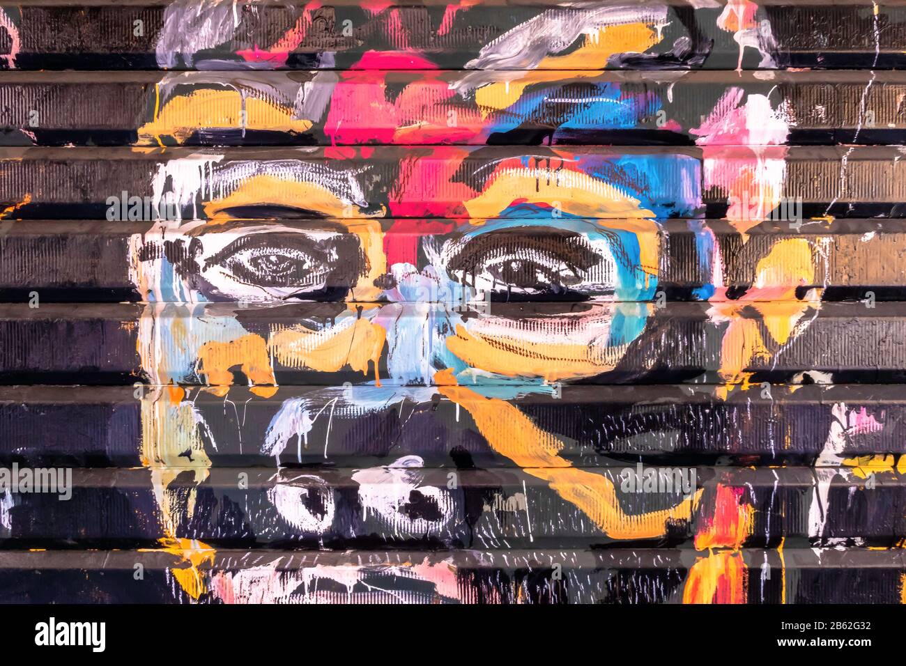 Graffiti with face of ethnic man on the old door of garage. Unknown ...