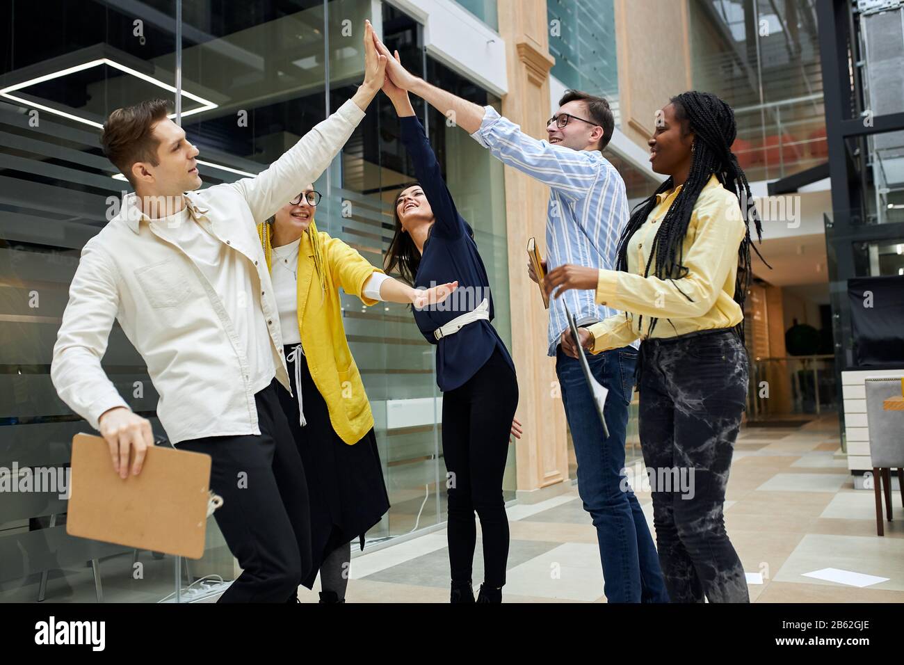 Motivated young cheerful people pledging support raising their hands ...