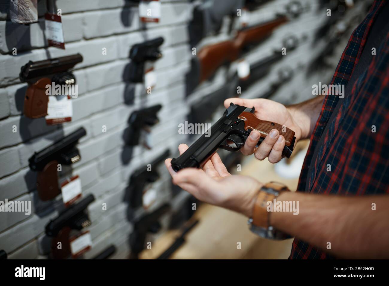 Man holds handgun in gun shop Stock Photo - Alamy