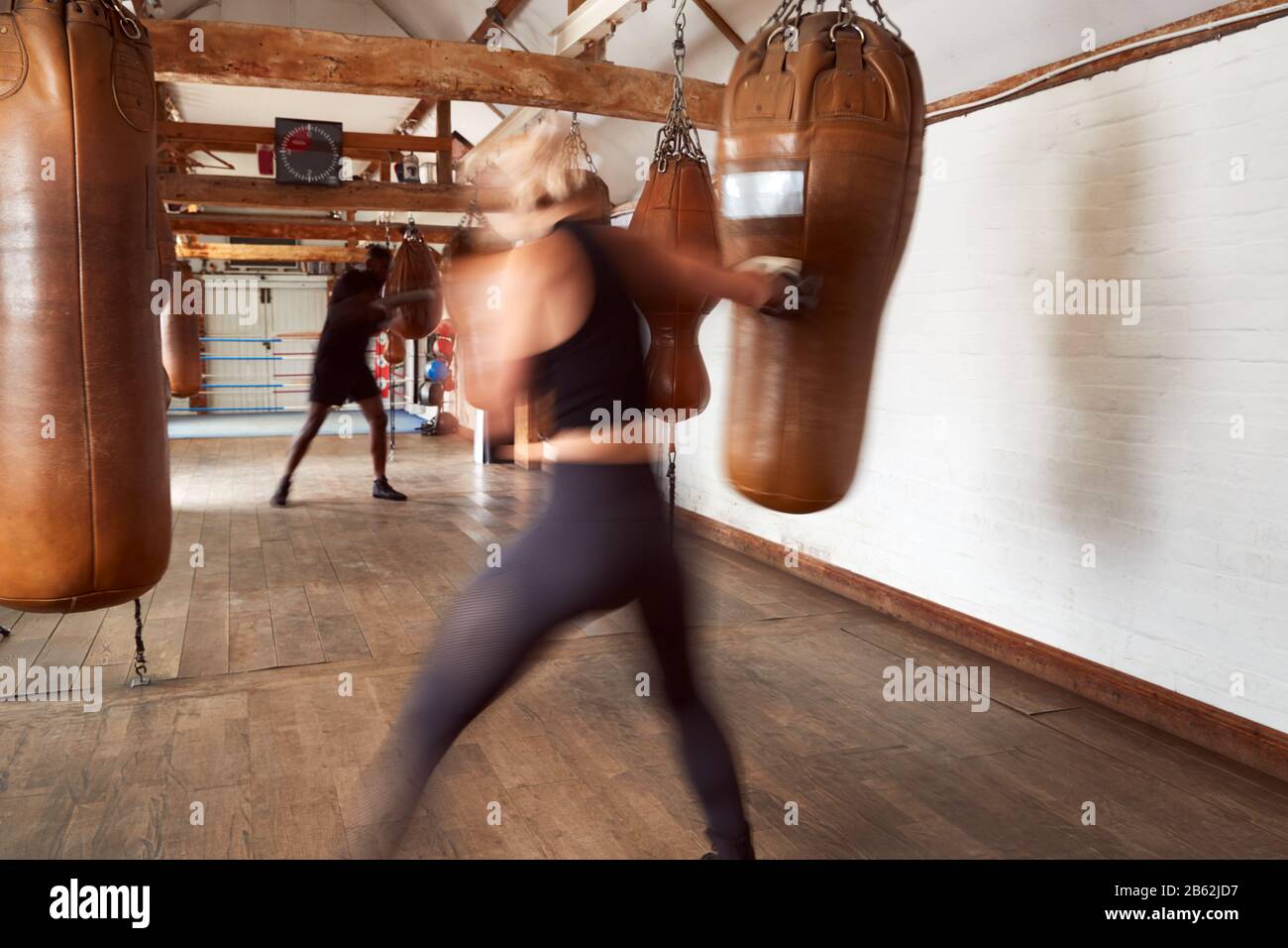 Action Shot Of Male And Female Boxers In Gym Training With Leather ...