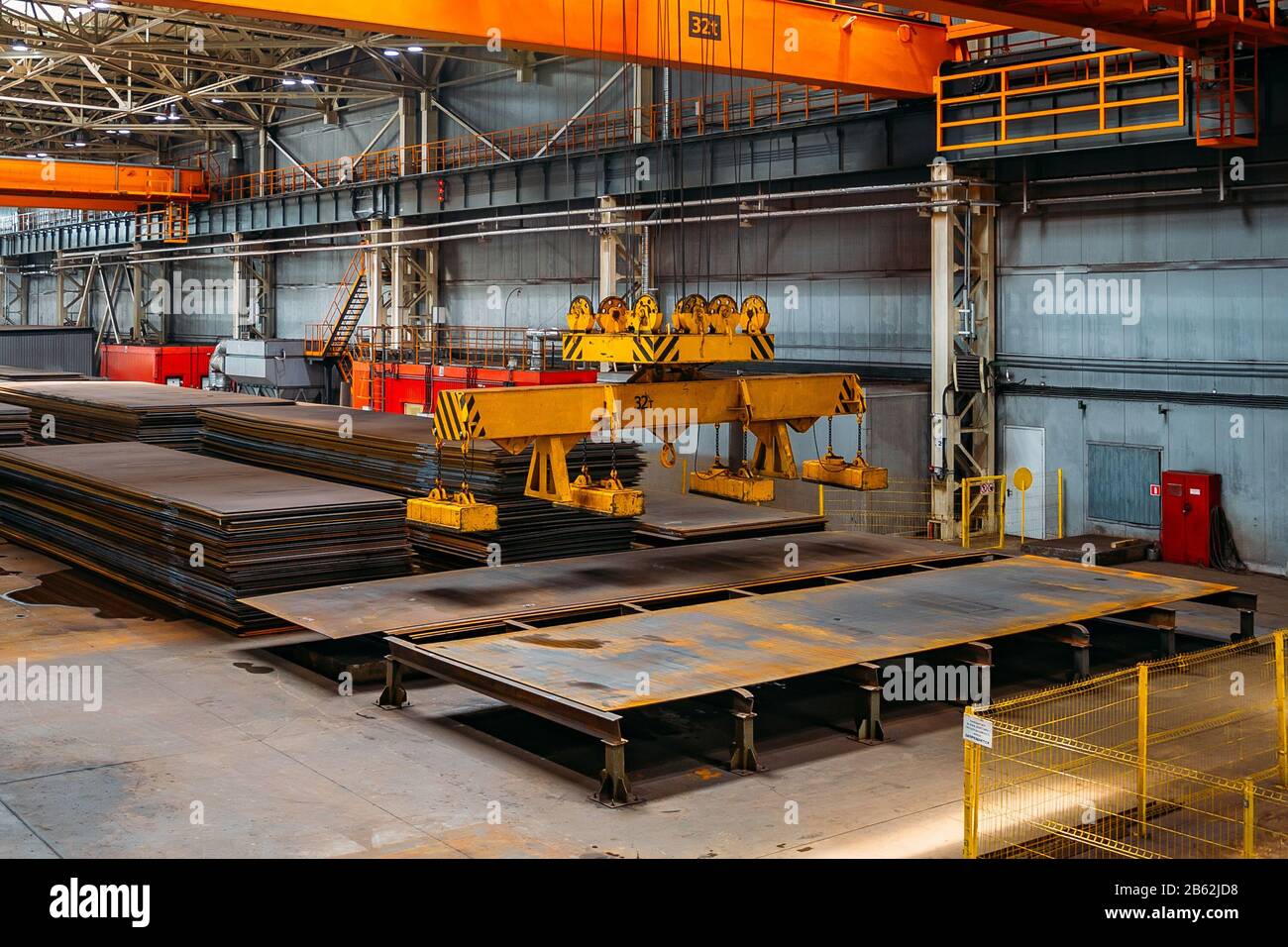 Overhead crane with electromagnetic beam grippers lifting steel sheets ...