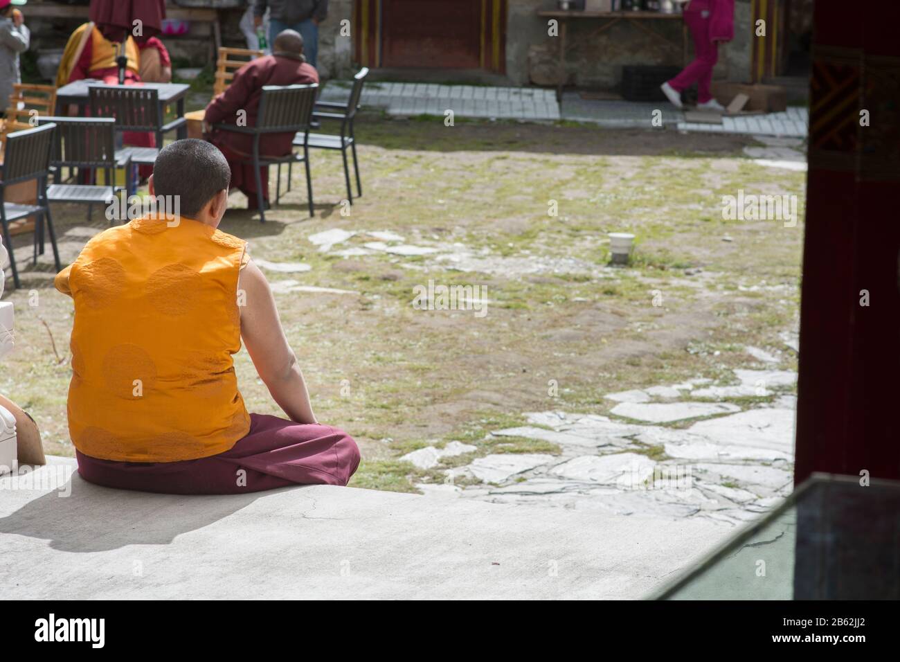 Tibetan monk, with back to the camera, sitting in a temple Stock Photo ...