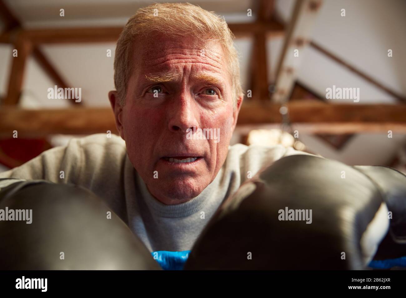 Senior Male Boxer In Gym Leaning On Ropes Of Boxing Ring Suffering From ...