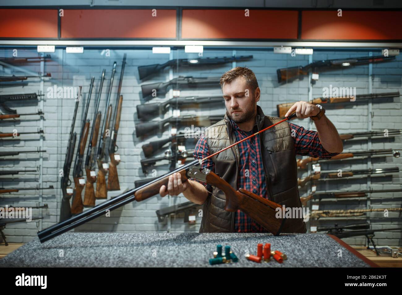 Man cleans rifle barrel at counter in gun shop Stock Photo - Alamy