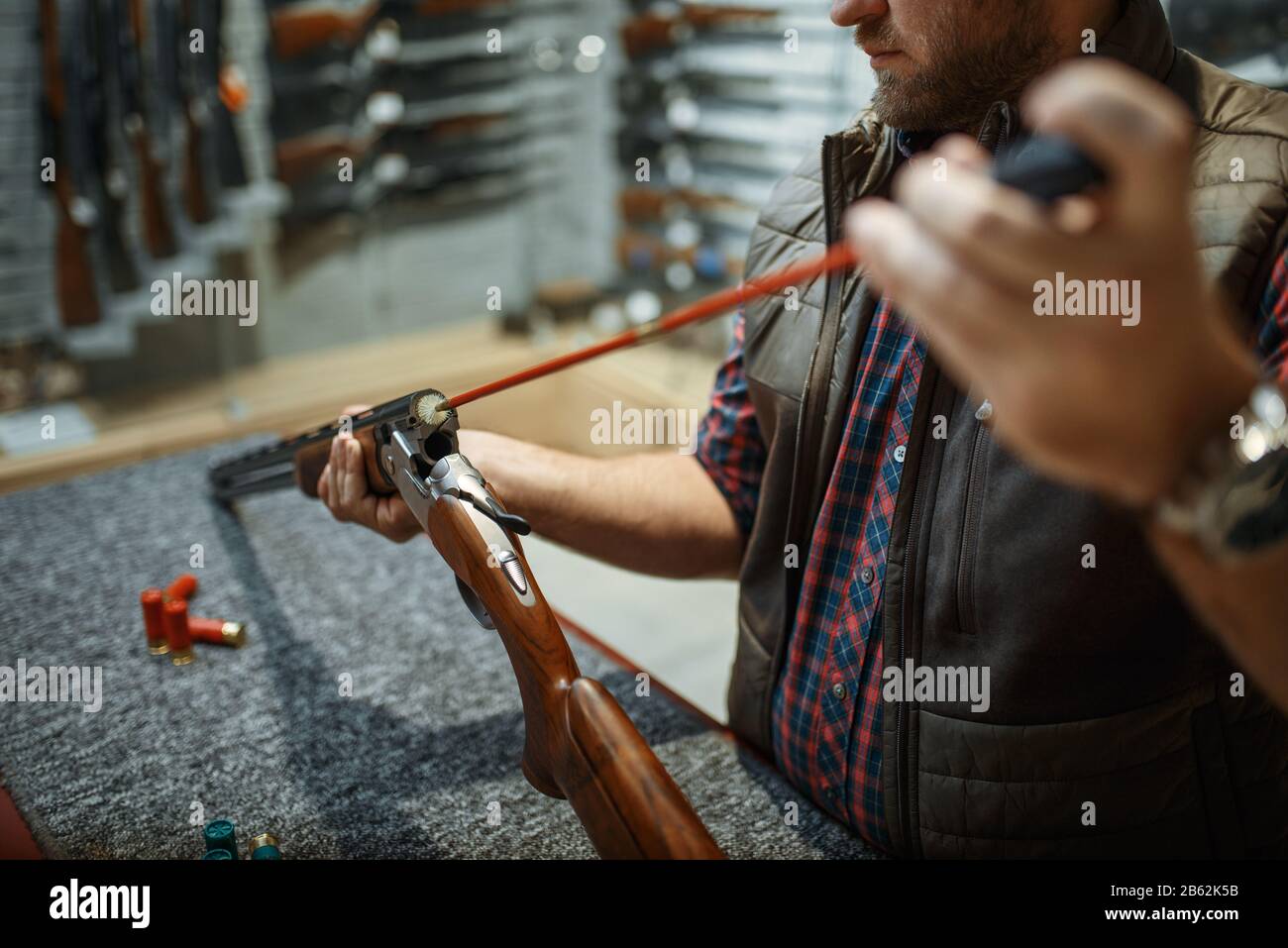Man cleans rifle barrel at counter in gun shop Stock Photo - Alamy