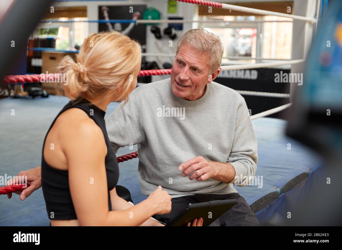 Female Personal Trainer With Senior Male Boxer In Gym Checking ...