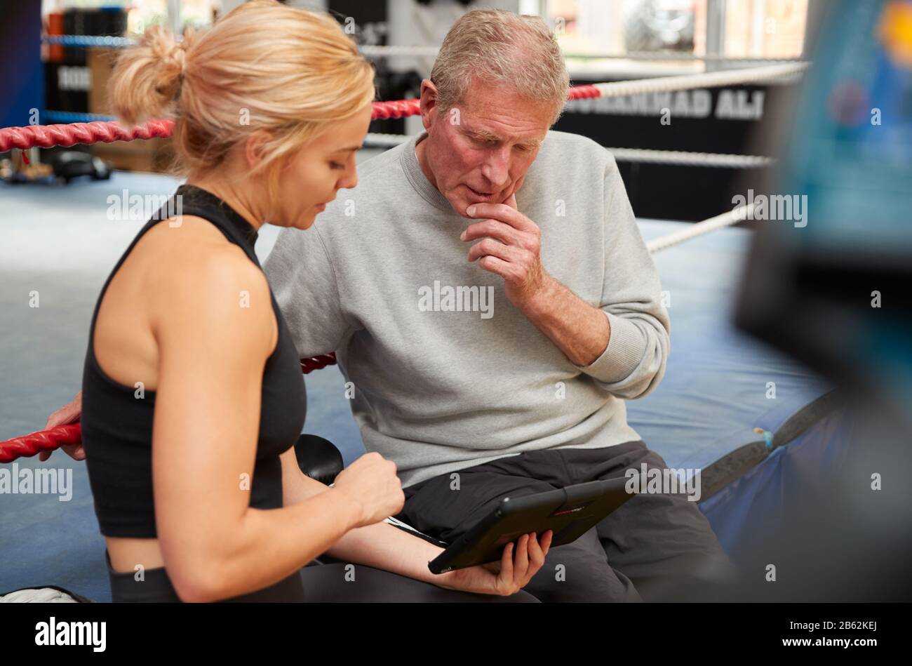 Female Personal Trainer With Senior Male Boxer In Gym Checking ...