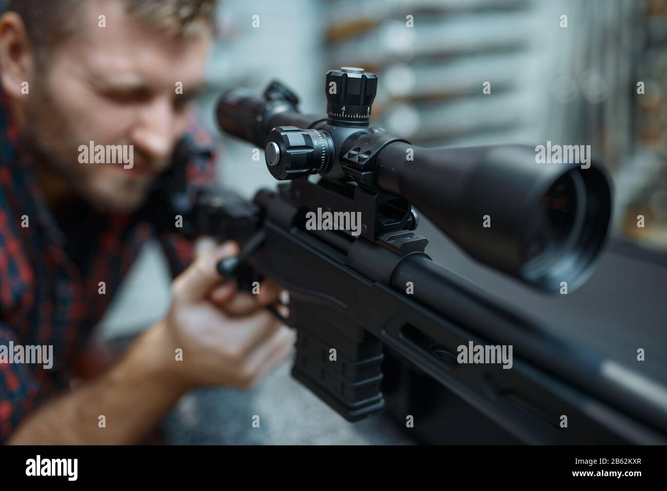 Man checks optical sight on sniper rifle, gun shop Stock Photo - Alamy