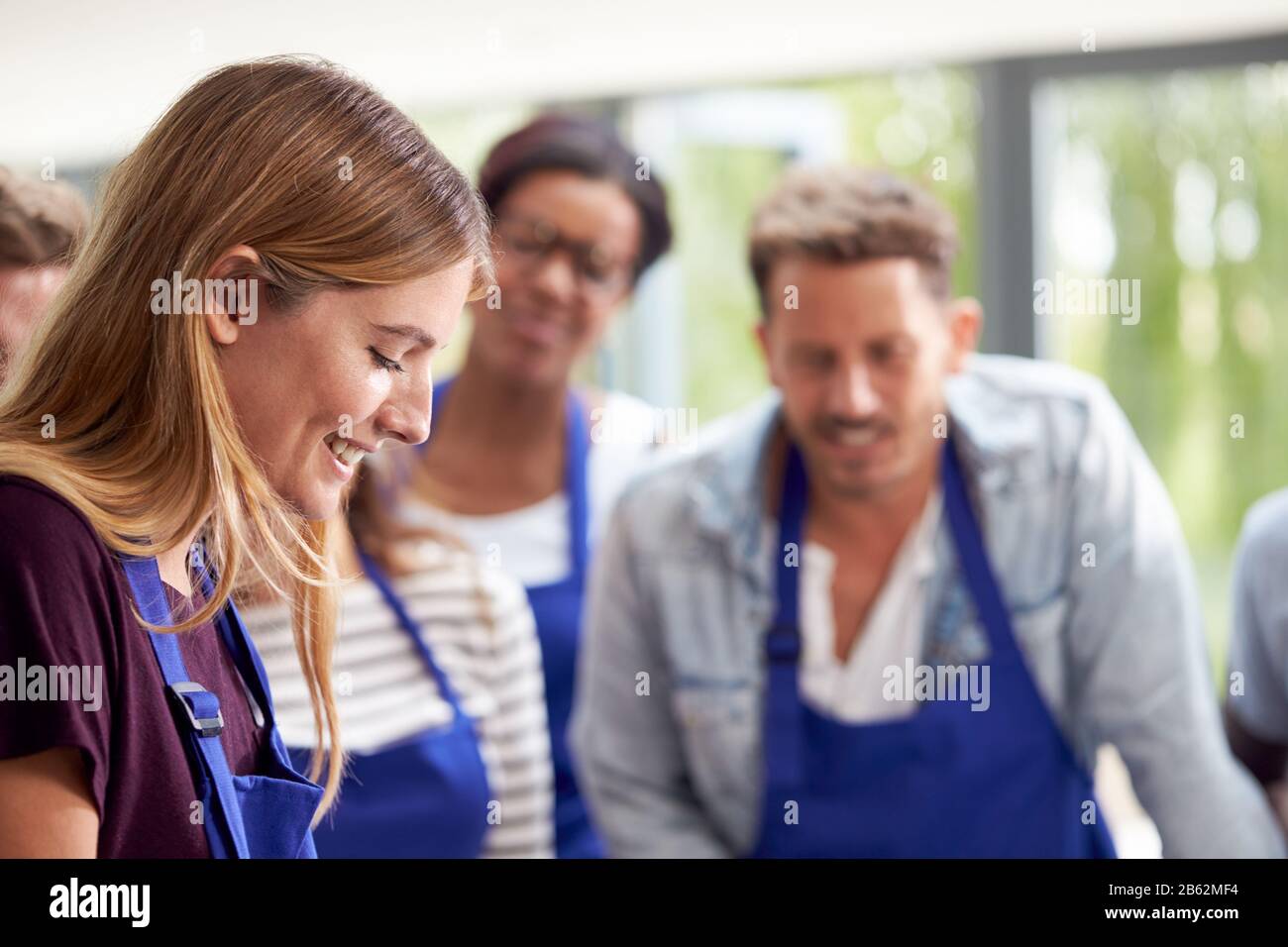 Students Watching Female Teacher Following Recipe In Cookery Class ...