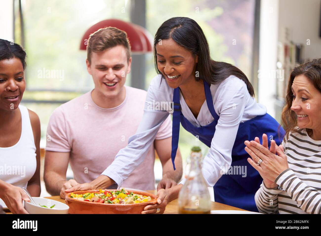 Group Of Friends Sitting Around Table Eating Meal At Home Together ...
