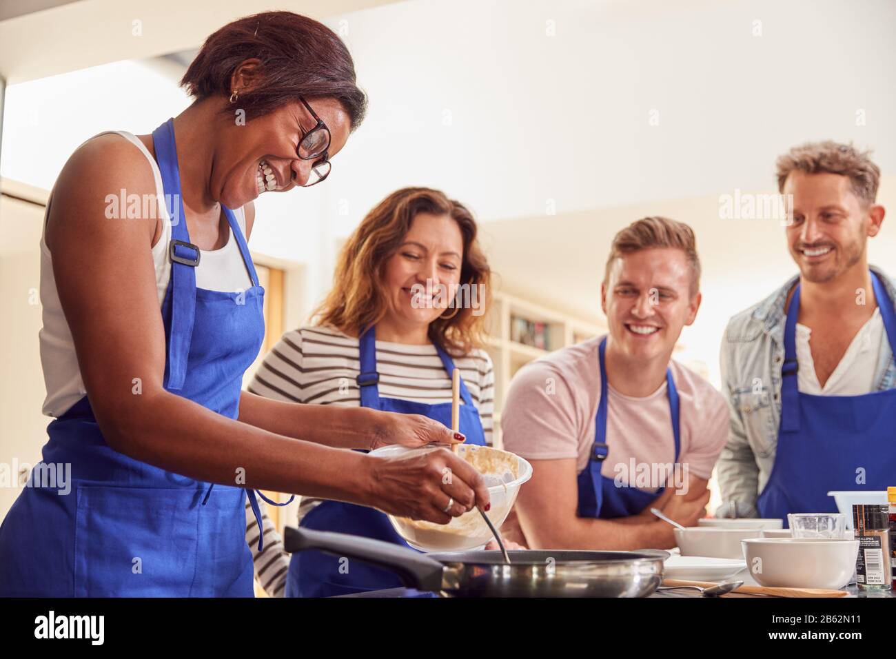 Female Teacher Making Pancake On Cooker In Cookery Class As Adult ...