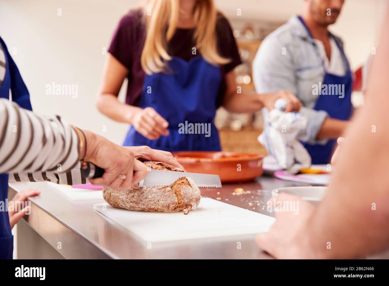 Close Of Woman Slicing Bread As Students Prepare Ingredients For Dish ...