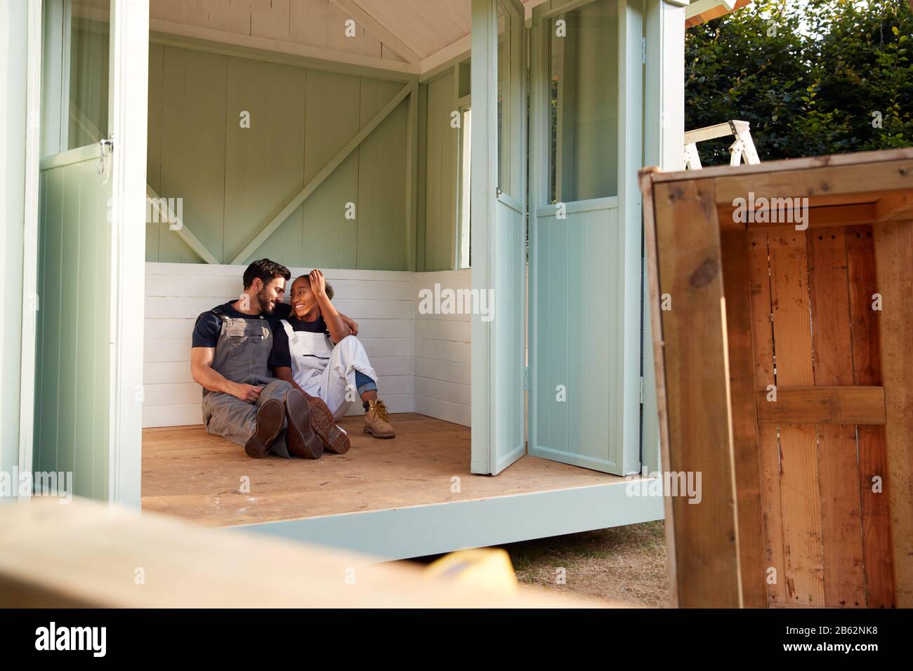 Couple Taking A Break From Building Outdoor Summerhouse In Garden Stock ...