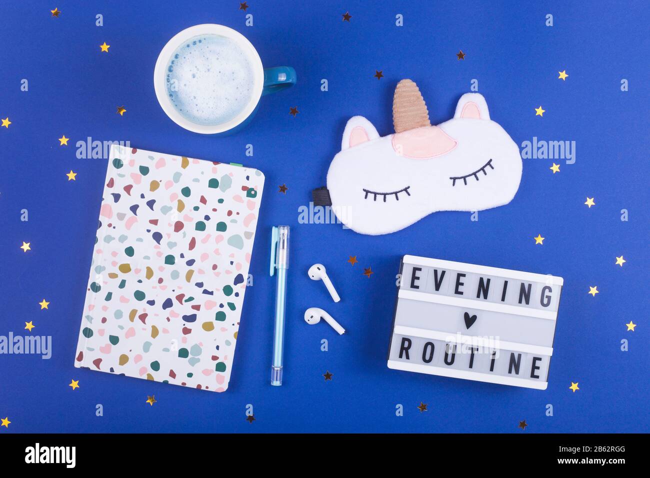 A mask for sleeping, a diary for notes and a cup of matches on a blue ...