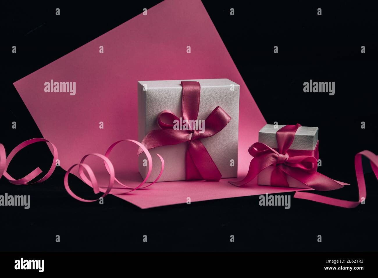 Present box with pink ribbon on the pink and black background Stock ...