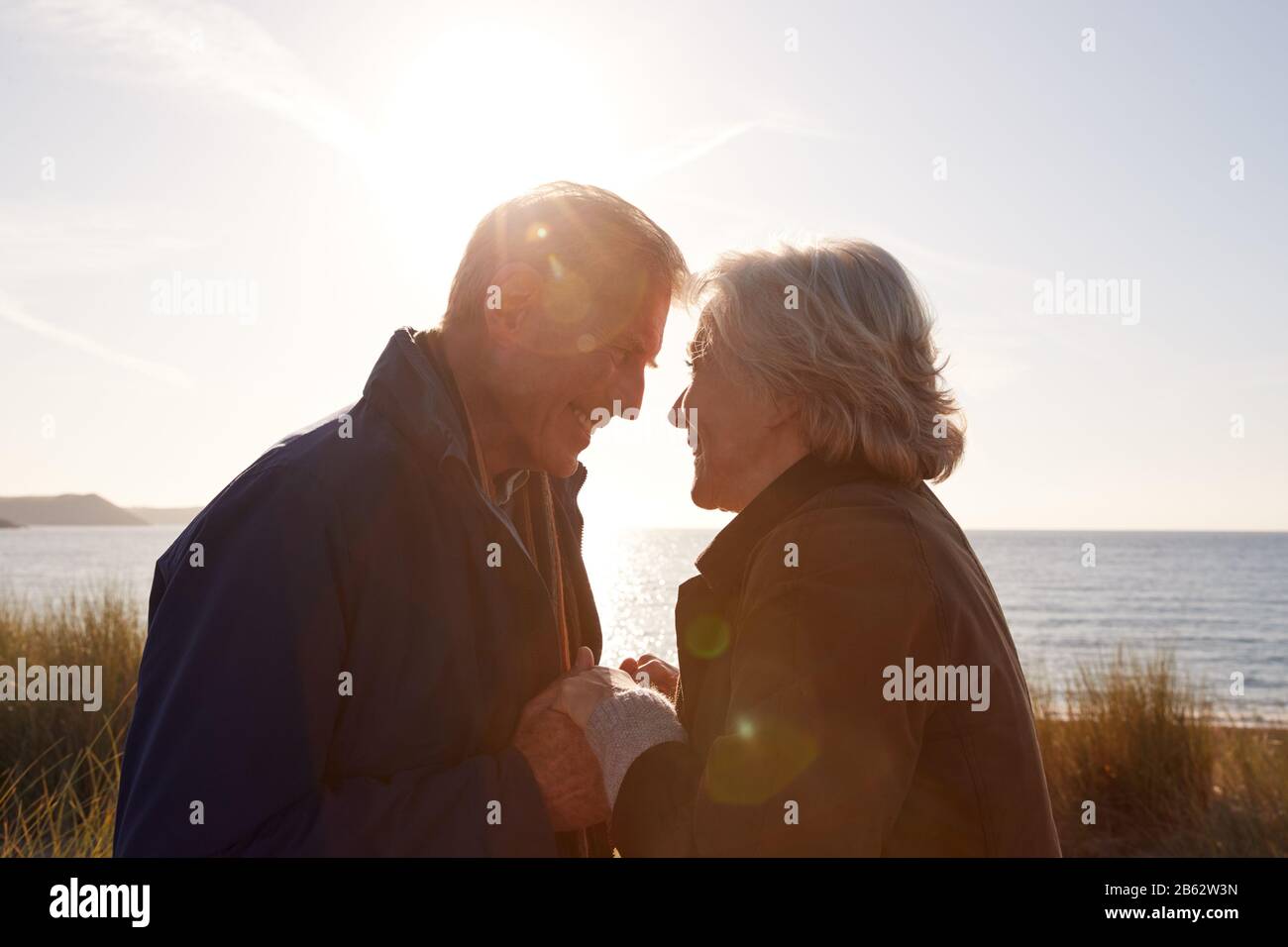 Loving Active Senior Couple Holding Hands As They Walk Through Sand