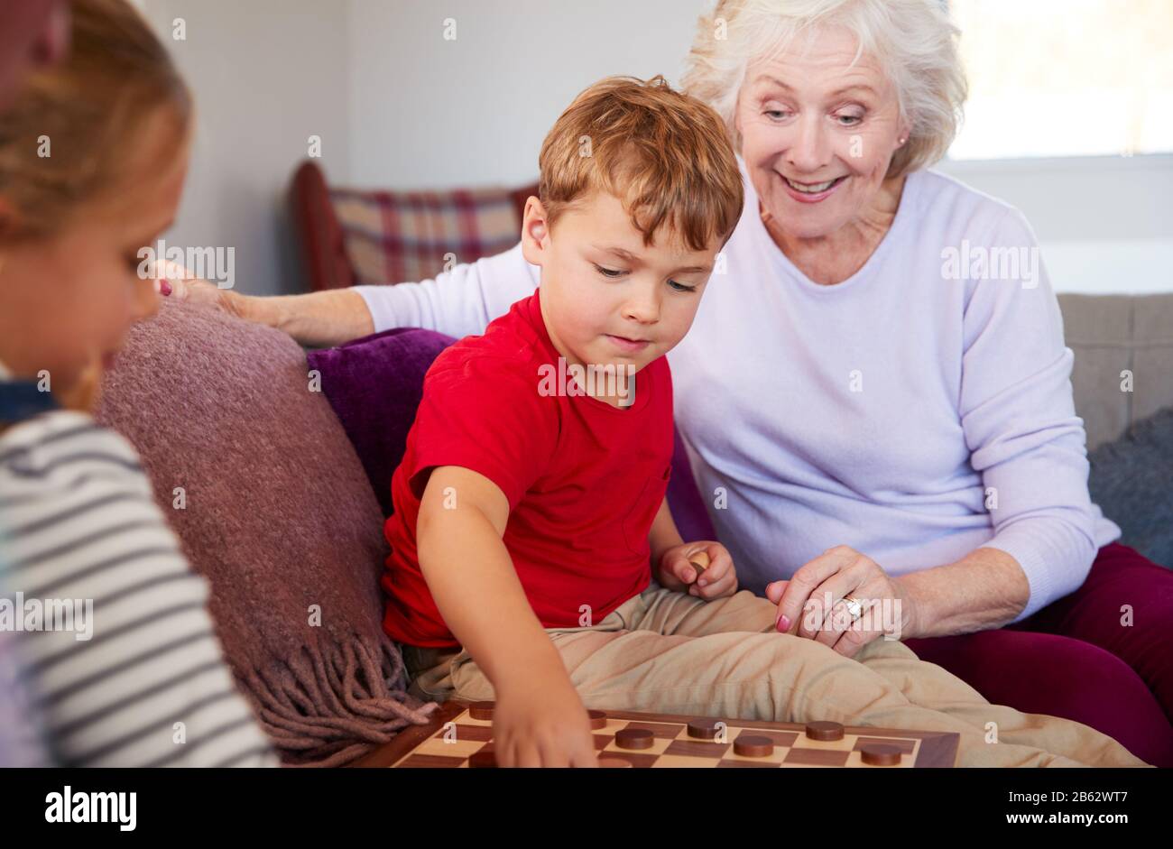 Grandparents Playing Board Game Of Draughts With Grandchildren At Home ...