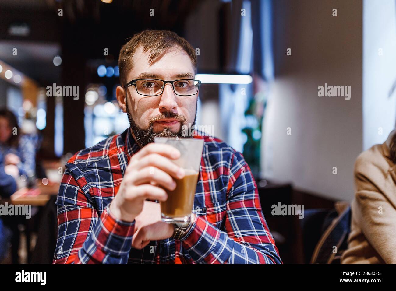 Hipster Man in glasses is drinking coffee in cafe Stock Photo - Alamy