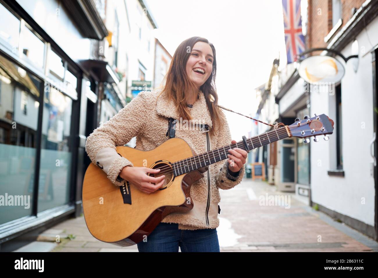 Female Musician Busking Playing Acoustic Guitar Outdoors In Street ...