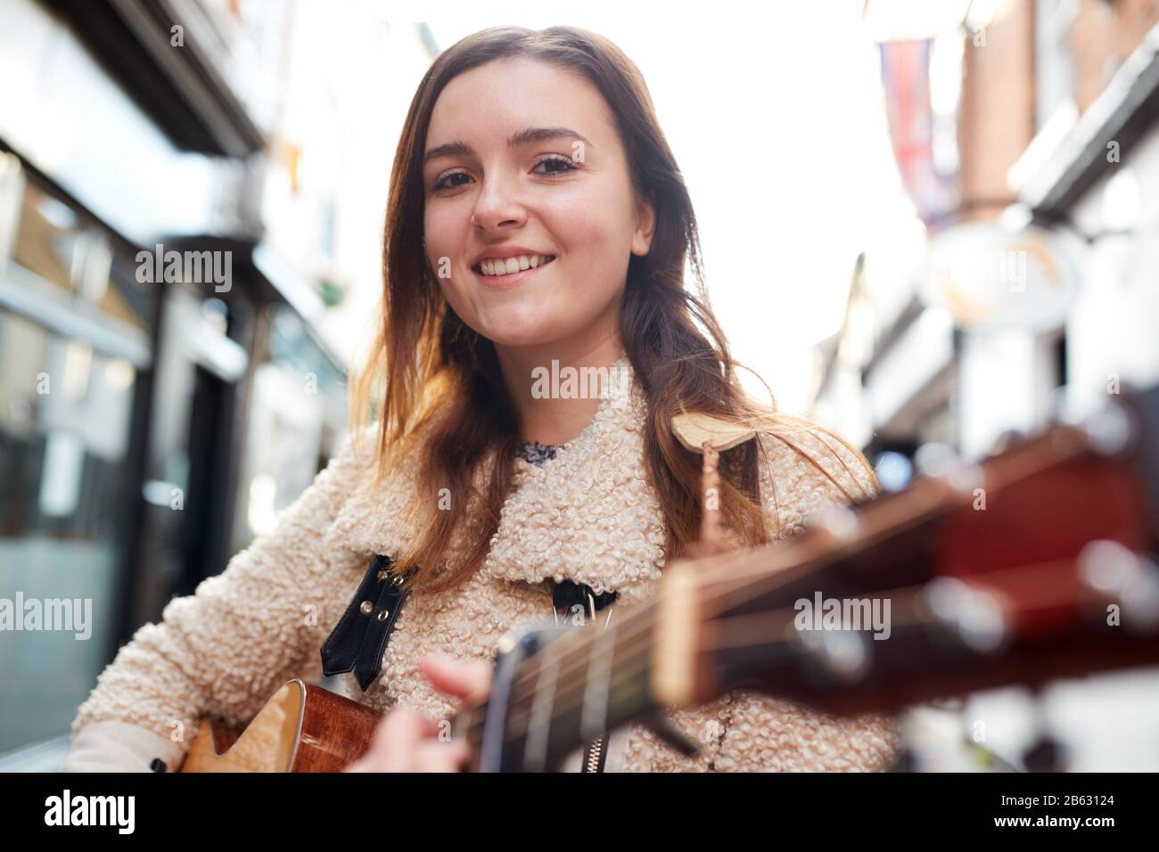 Portrait Of Young Female Musician Busking Playing Acoustic Guitar And ...