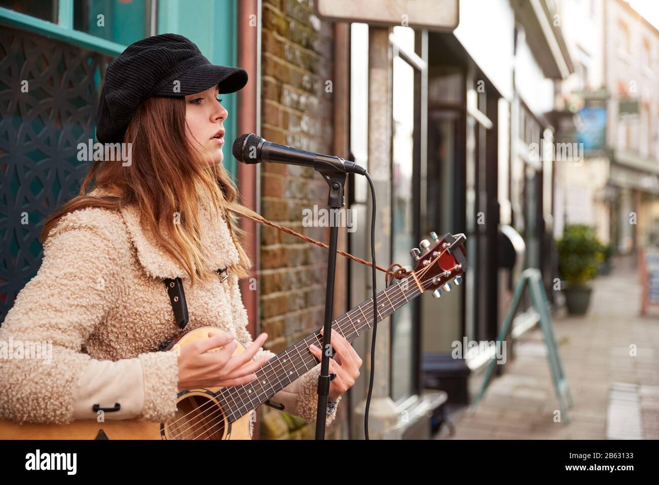 Female Musician Busking Playing Acoustic Guitar And Singing Outdoors In ...