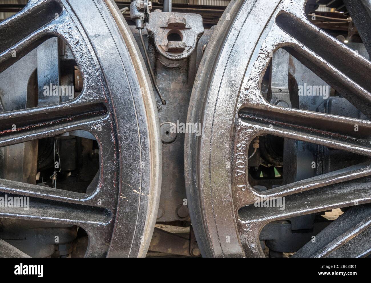 Horizontal close-up of two massive iron steam locomotive engine wheels ...