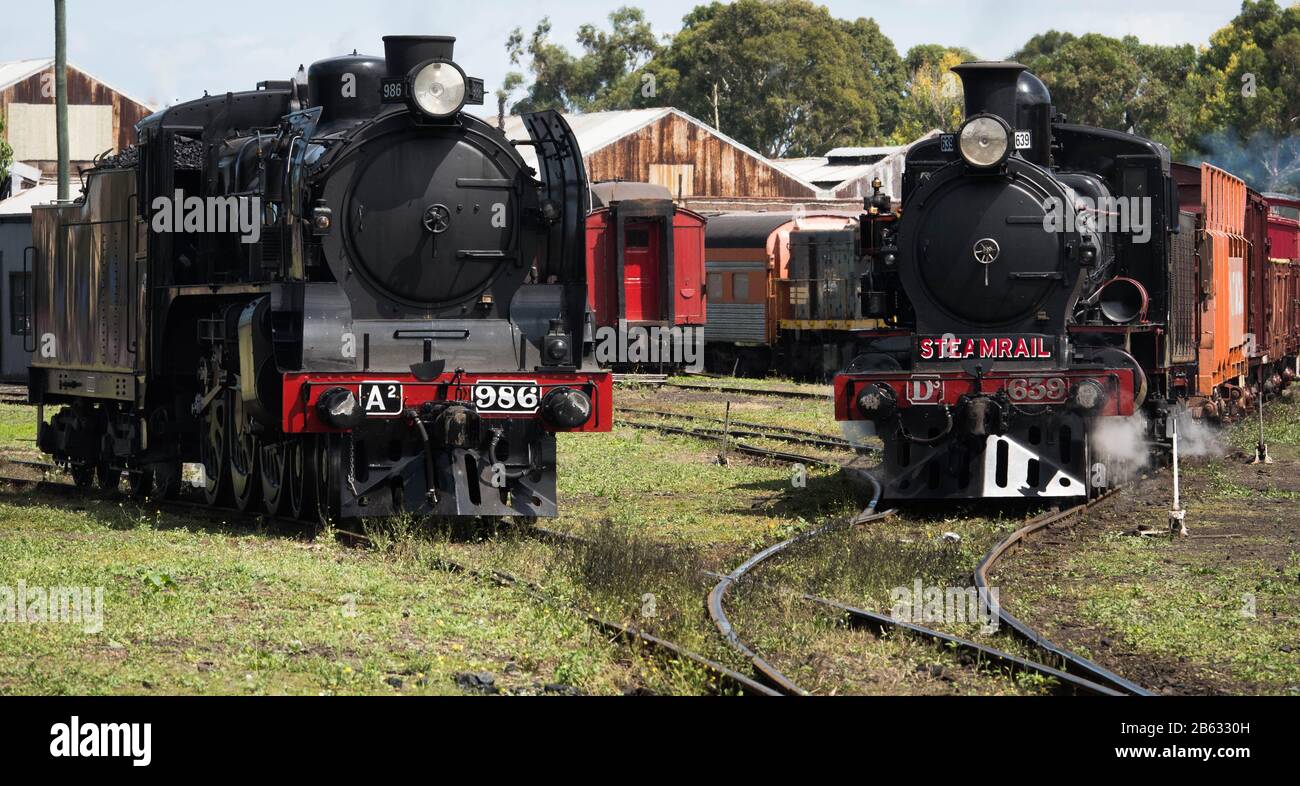 Brightly painted red and black steam engines with belching smoke and ...