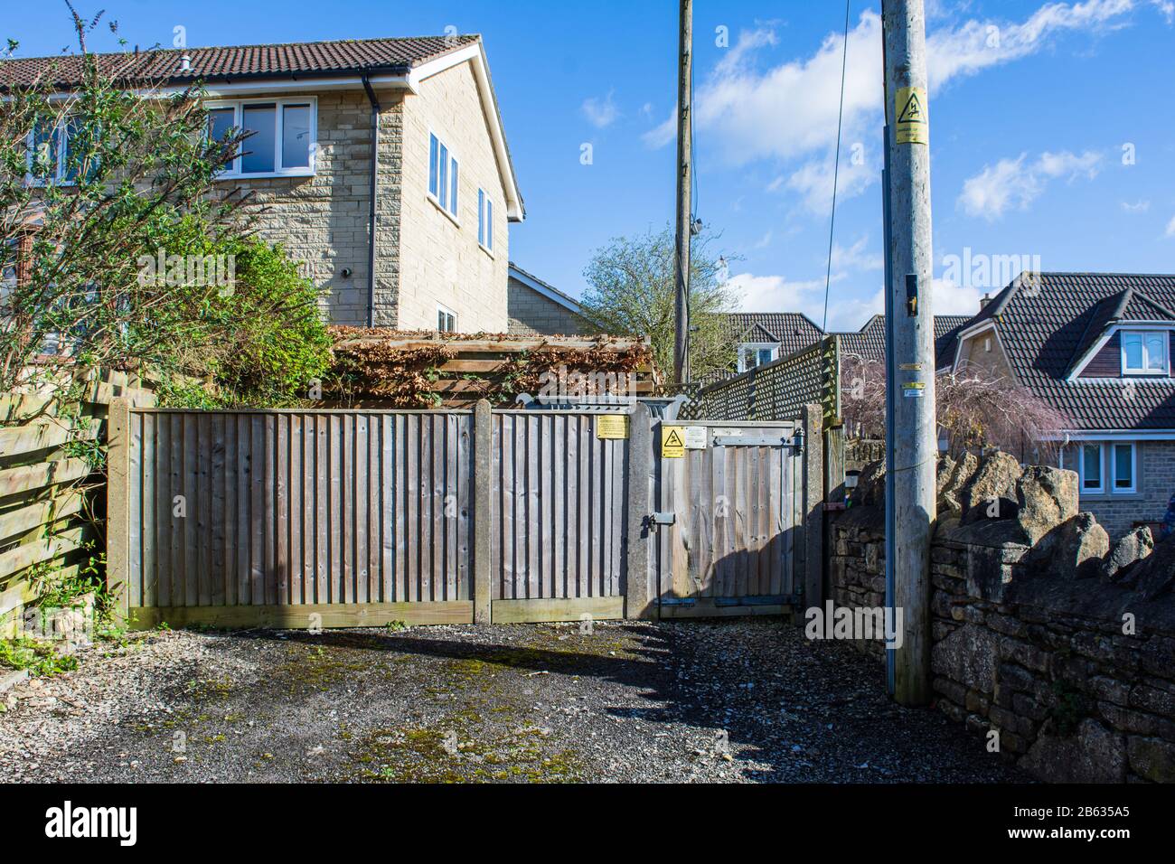 A wooden fence with padlocked gate and warning signs around an ...