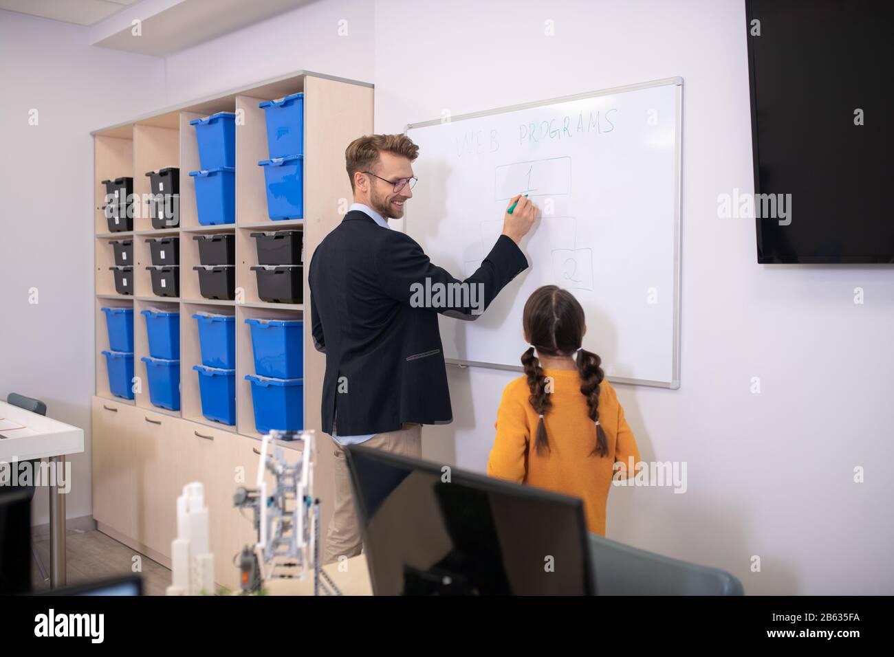 Male teacher writing on whiteboard, explaining, smiling Stock Photo - Alamy