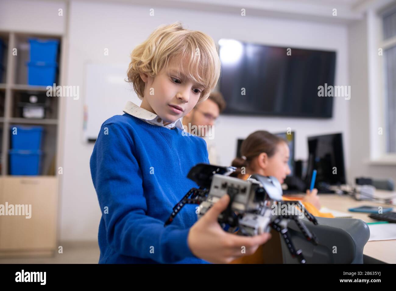 Boy holding building kit, teacher and girl in background Stock Photo ...