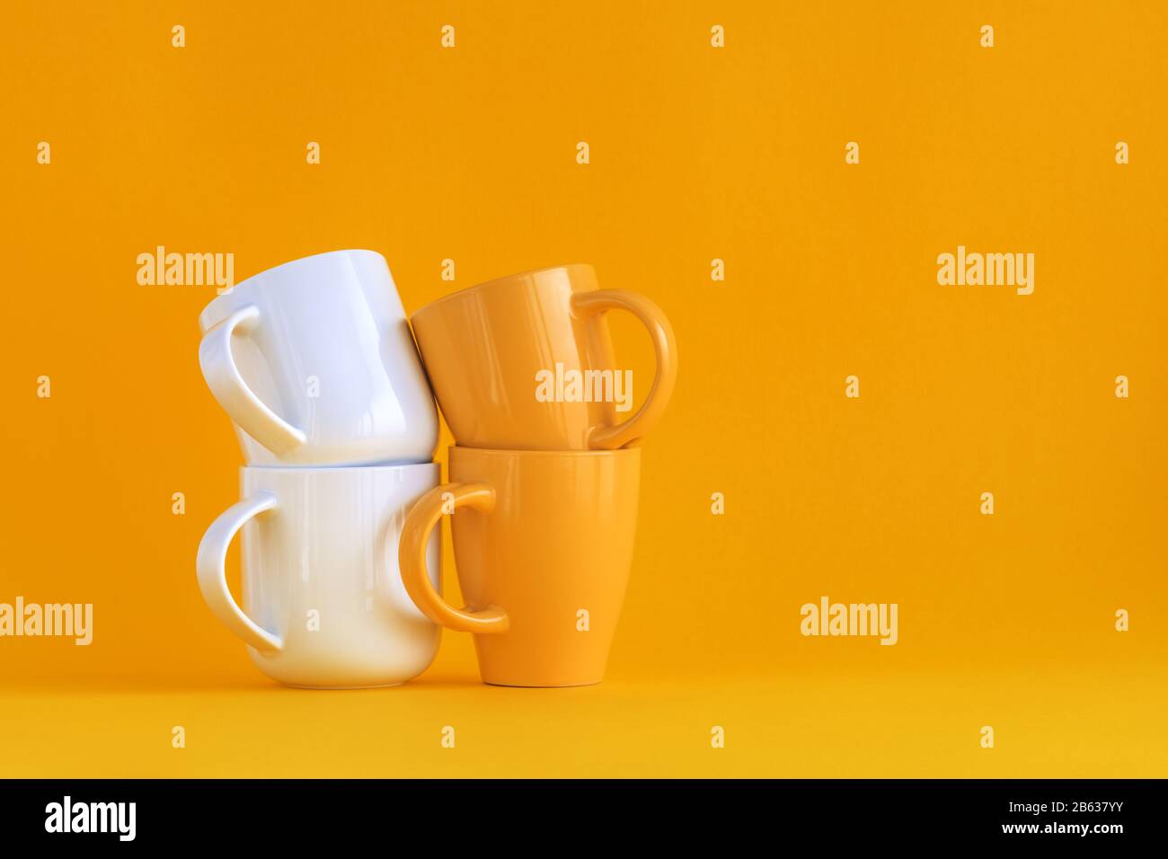 White and yellow coffee cups stack on yellow background with copy space ...