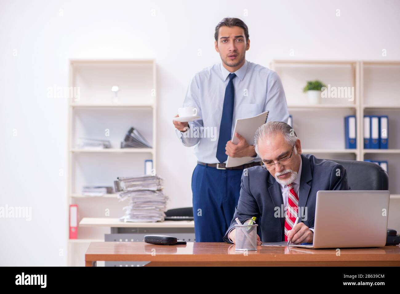 Old boss and young employee in the office Stock Photo - Alamy
