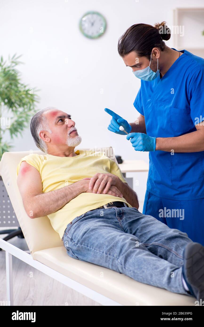Injured old man visiting male doctor traumatologist Stock Photo - Alamy