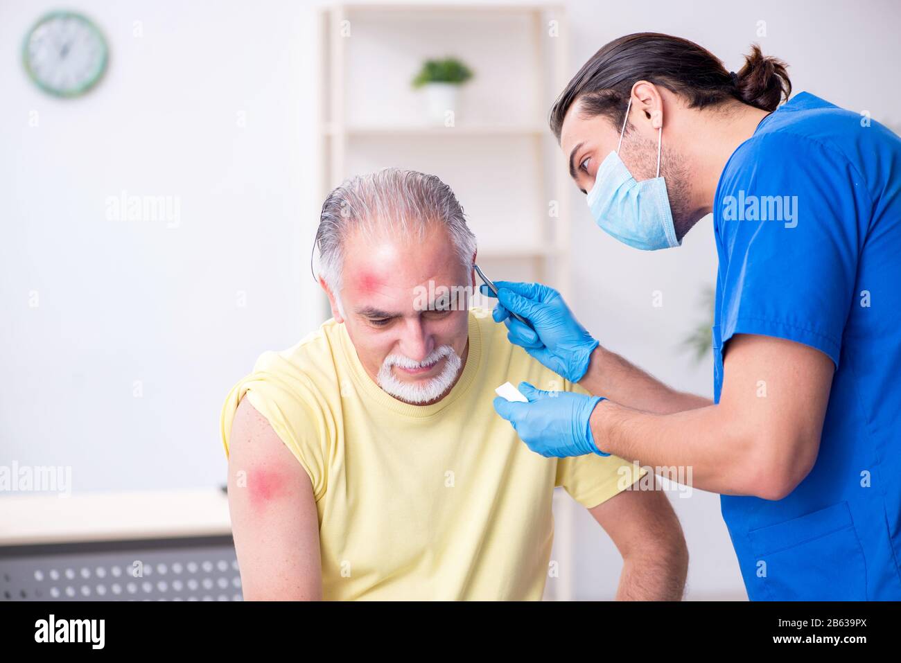 Injured old man visiting male doctor traumatologist Stock Photo - Alamy