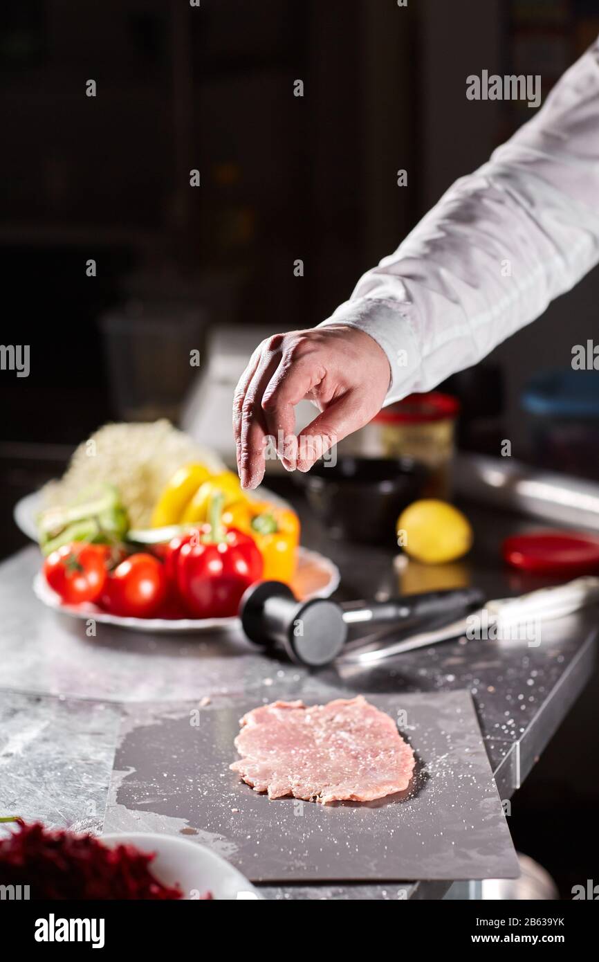 Chief chops and marinates pork. Professional chef in a kitchen of ...