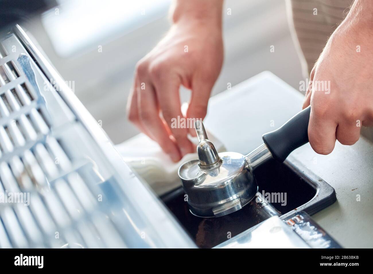 Cropped view of skilled young adult barista working in cafe, cleaning ...