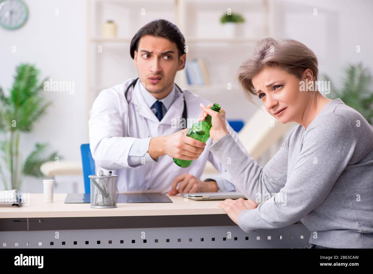 The female alcoholic visiting young male doctor Stock Photo - Alamy