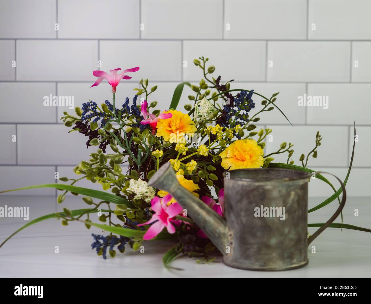 Rustic metal watering can and spring floral wreath on a sandstone ...