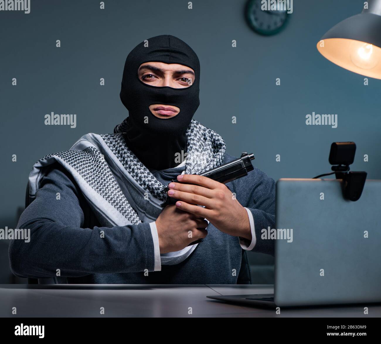 The terrorist burglar with gun working at computer Stock Photo - Alamy
