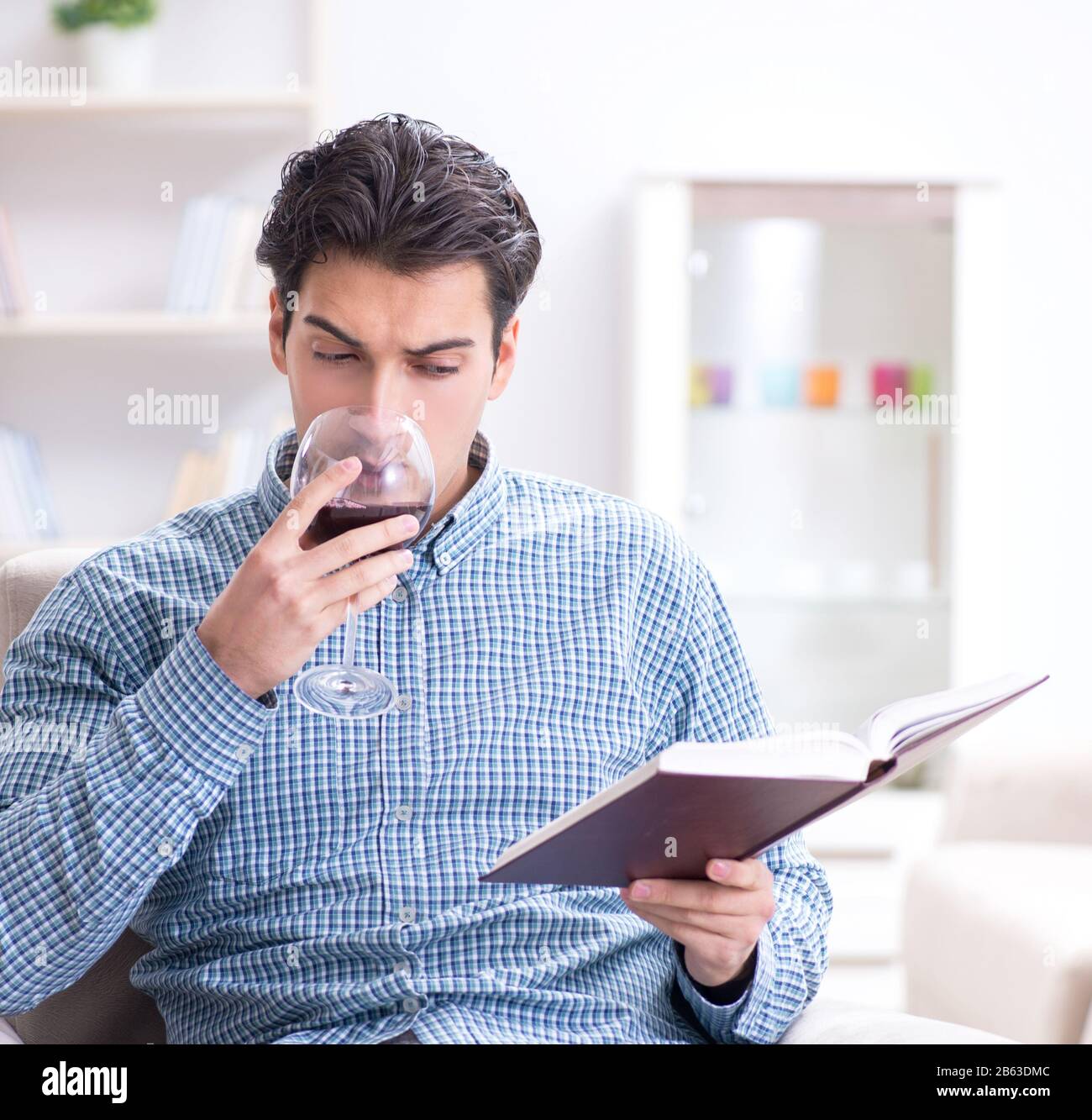 The young man drinking wine at home Stock Photo - Alamy