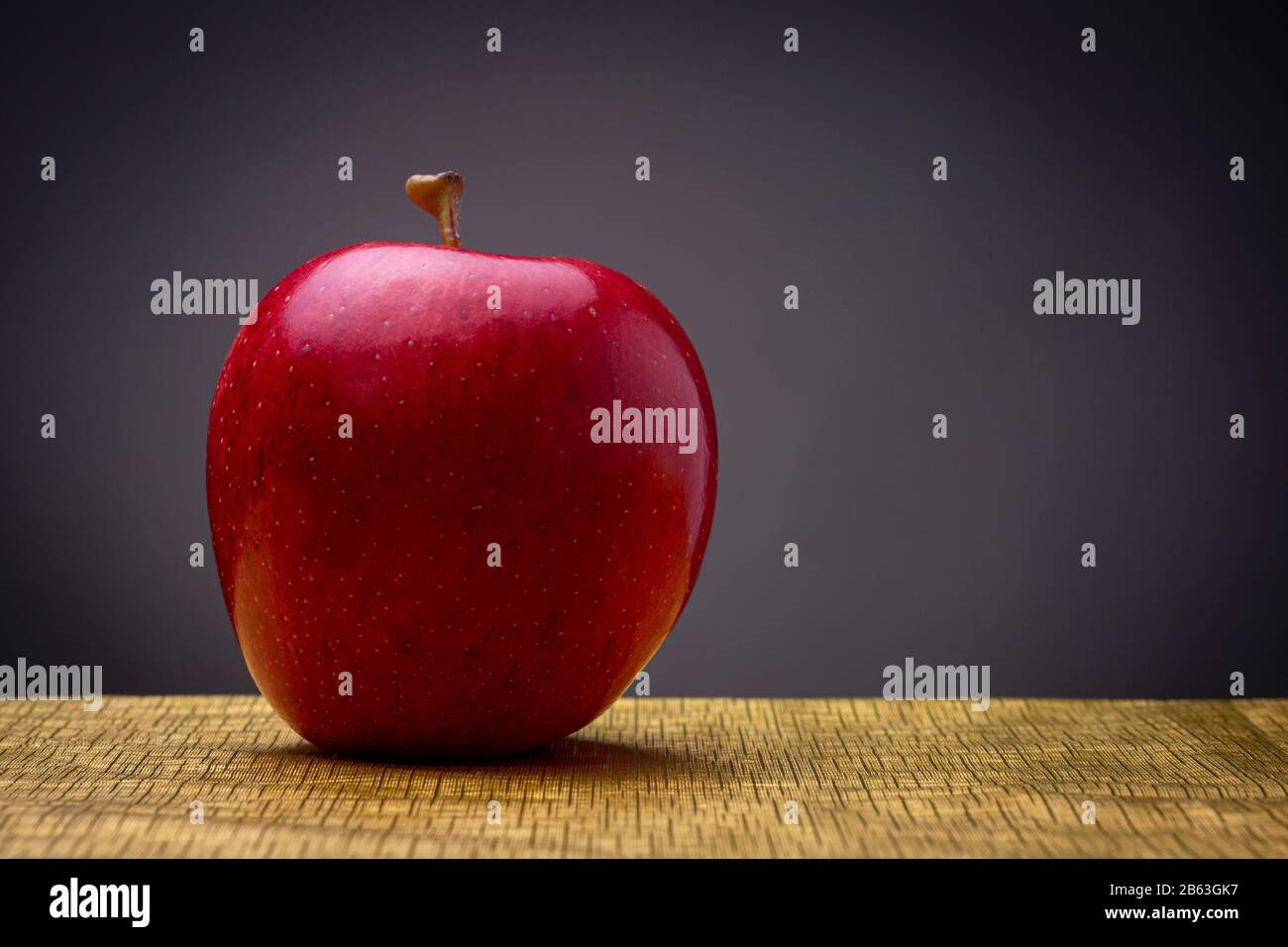 Vibrant bright red apple against dark studio background Stock Photo - Alamy